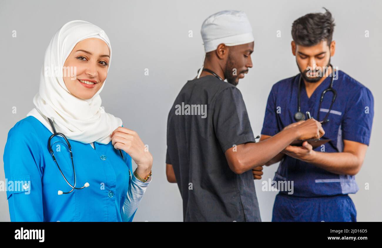 Group of paramedics smiling over gray background. muslim doctor woman ...