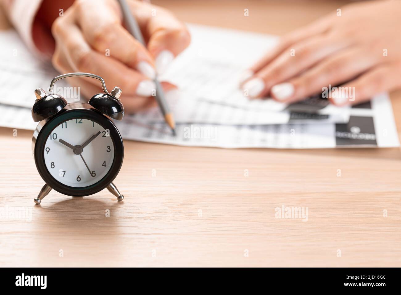 alarm clock with time running out. Students hands to take exams, write ...