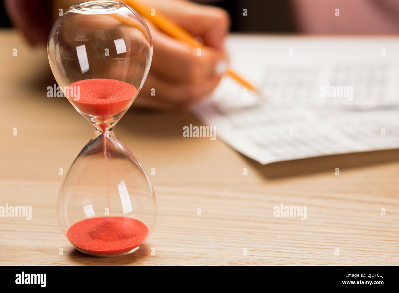 Hourglass with time running out and student hand testing in exercise ...
