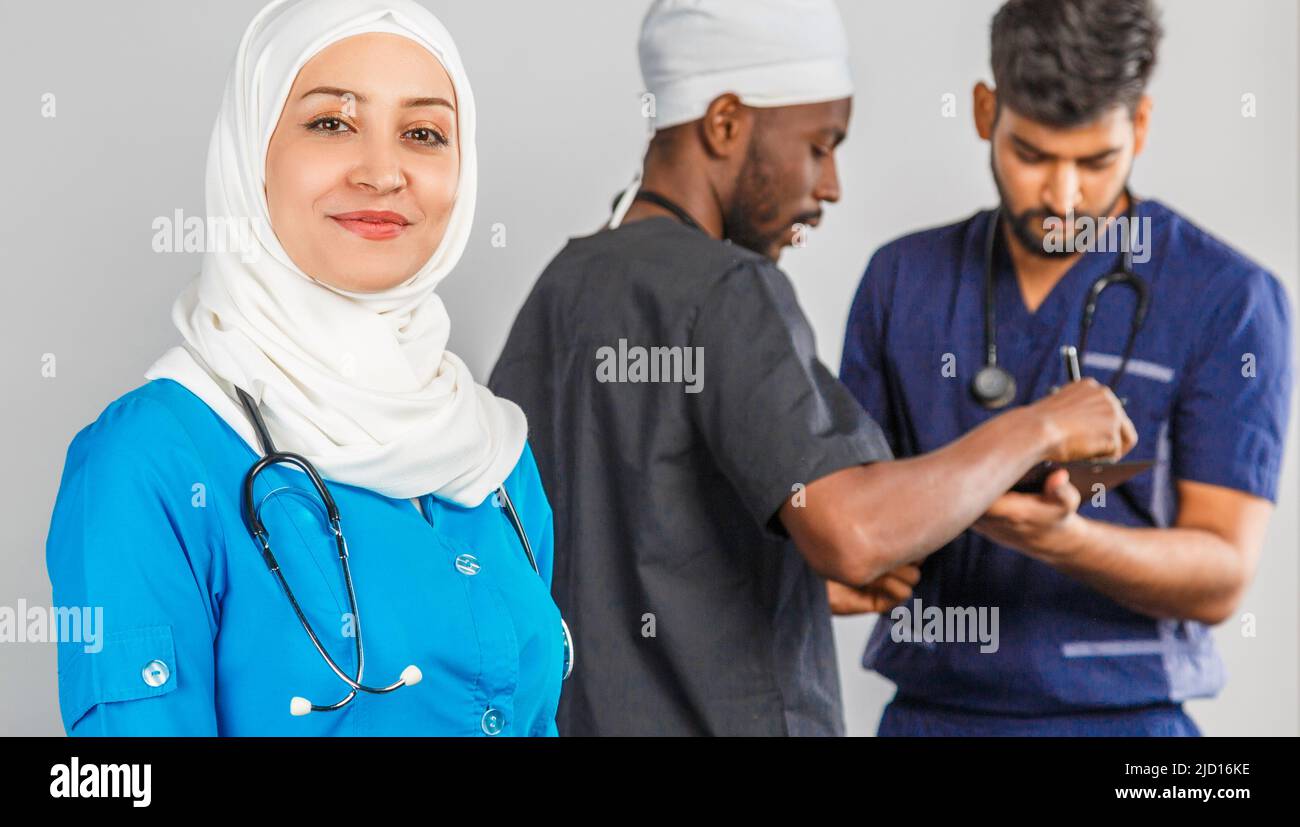Group of paramedics smiling over gray background. muslim doctor woman ...