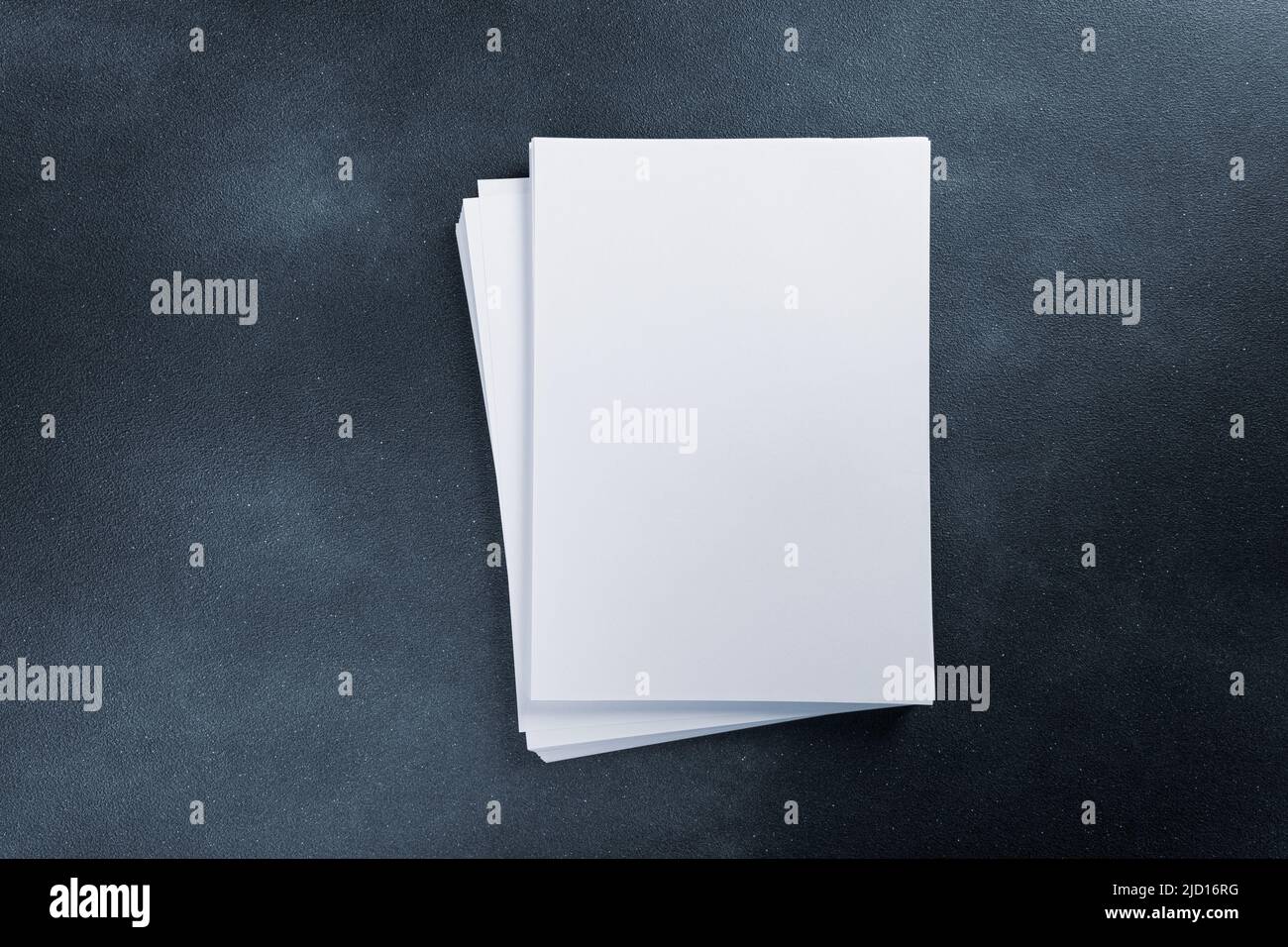 White business card sheet of paper a4 stack on a dark table. cold toned ...
