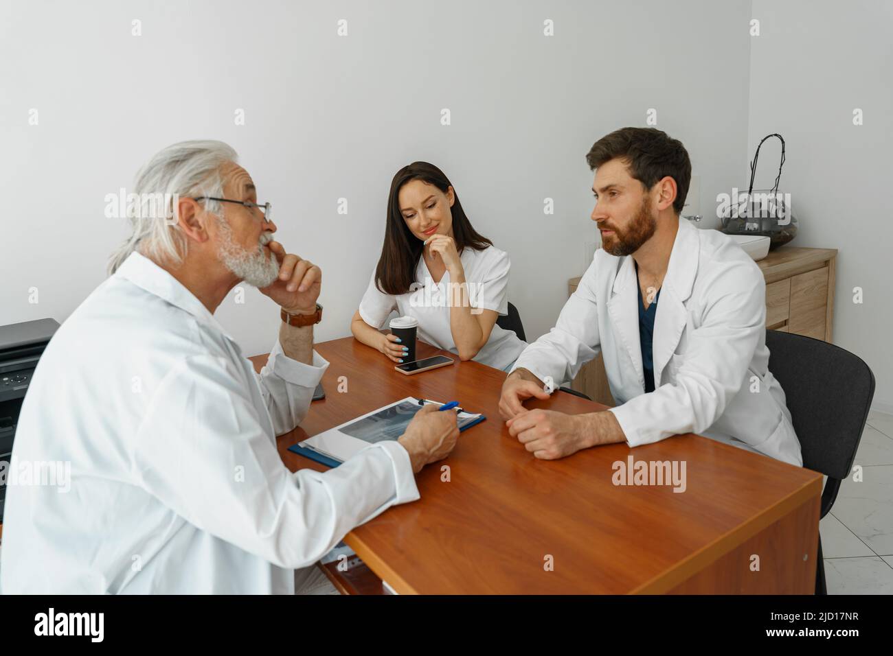 Group of doctors sitting at meeting table in conference room during ...