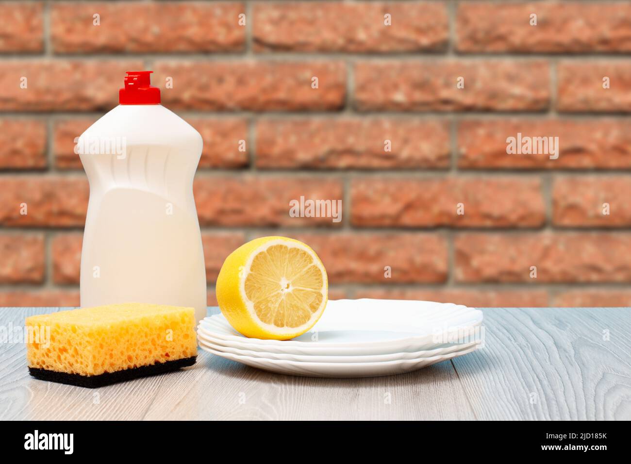 Plastic bottle of dishwashing liquid, a sponge, clean plates and a ...