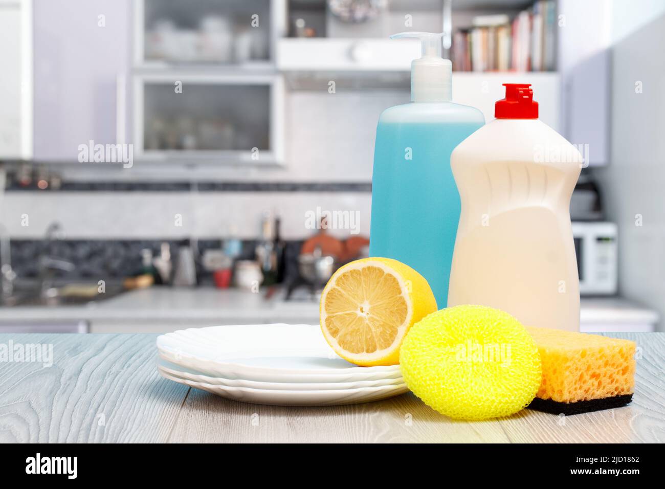 Plastic bottle of dishwashing liquid, sponges, clean plates and lemon ...