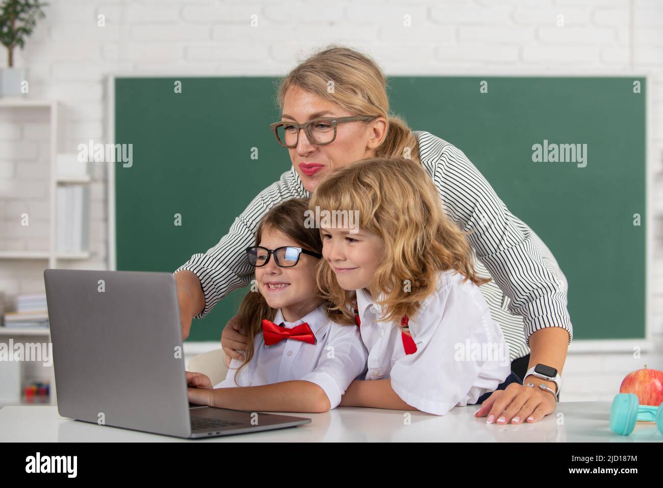 School teacher with a schoolkids learning at laptop computer. Teacher ...