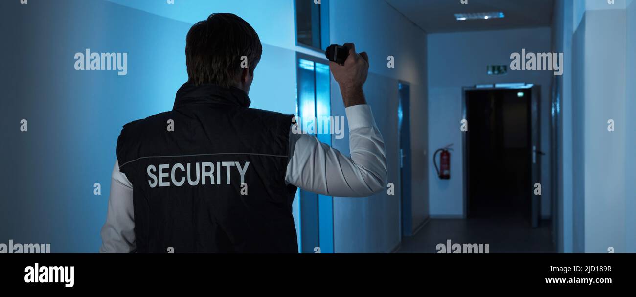 Rear View Of A Security Guard Standing In Corridor Of The Building ...