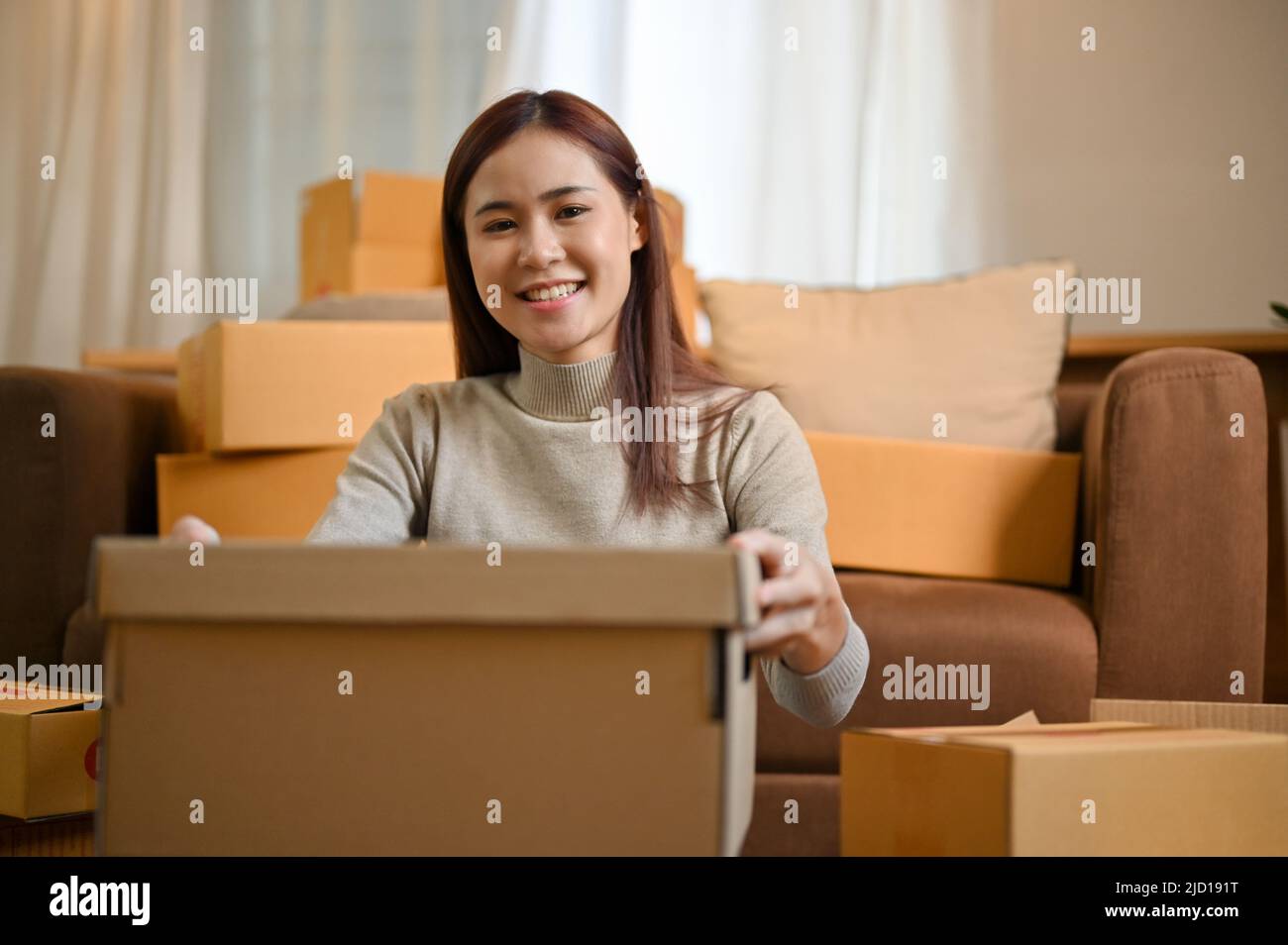 Happy millennial Asian woman packing her stuff in a cardboard box in ...