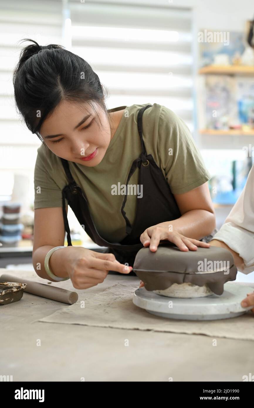 Portrait, A beautiful charming young Asian woman making moulding clay ...