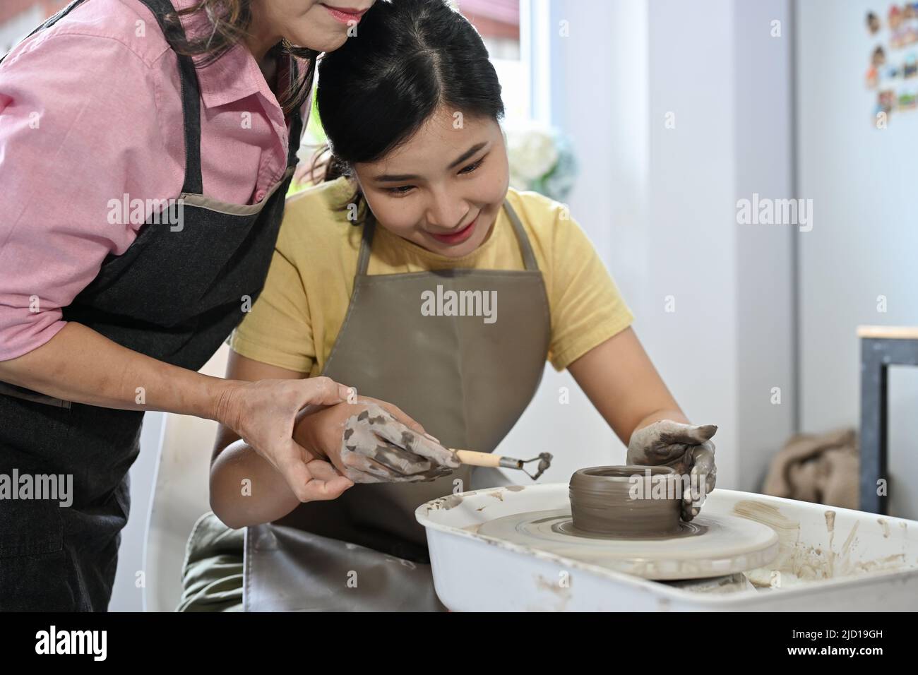 Professional asian aged woman craftsman teaching a beautiful young ...