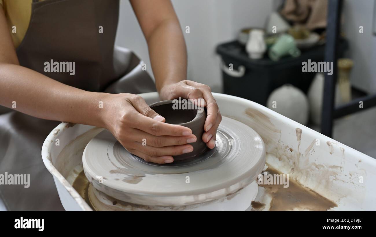 Woman potter hands making a ceramic cup on potter's wheel, moulding ...