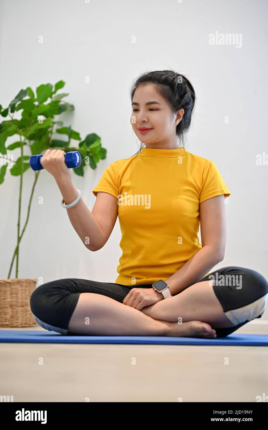 Portrait of a beautiful healthy young Asian woman in sportswear sits on ...