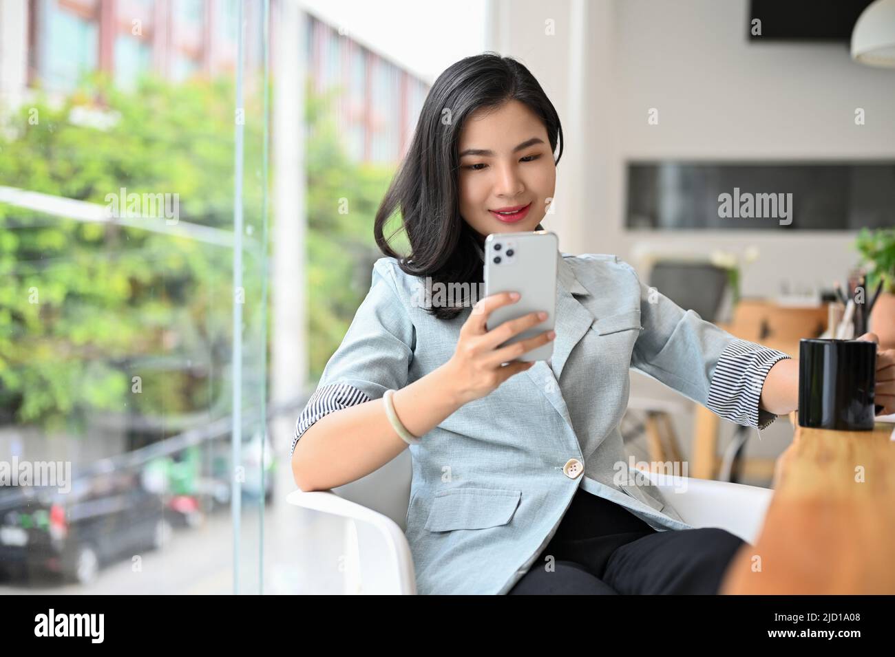 Attractive asian businesswoman or female manager sipping morning coffee ...