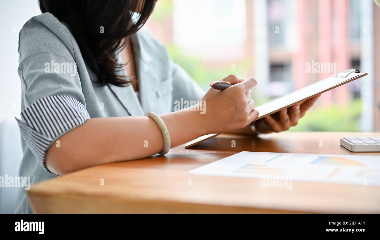 A businesswoman reading a business report, checking and reviewing an ...