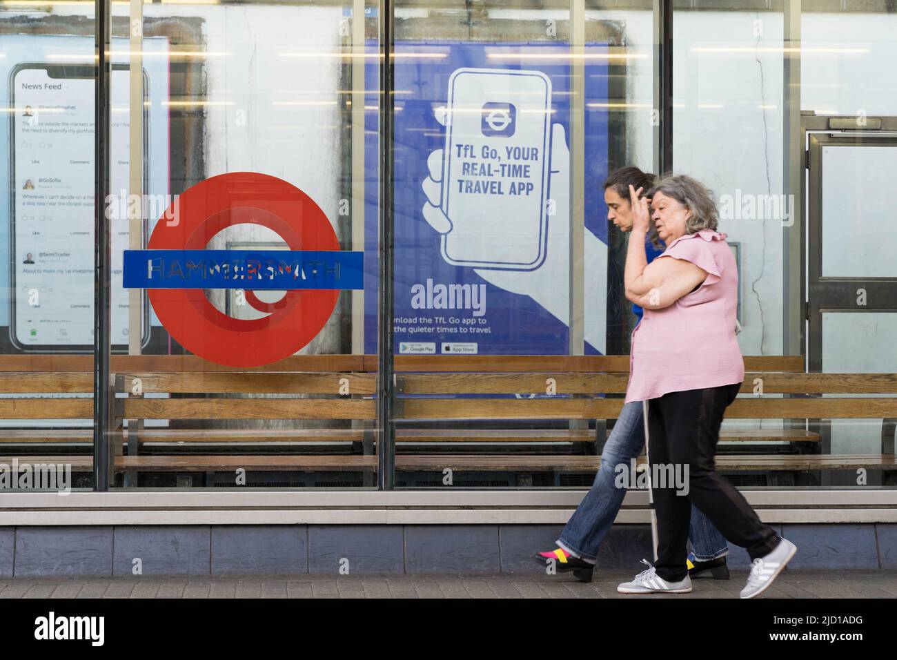 man and woman walk on the underground platform with roundel sign and ...
