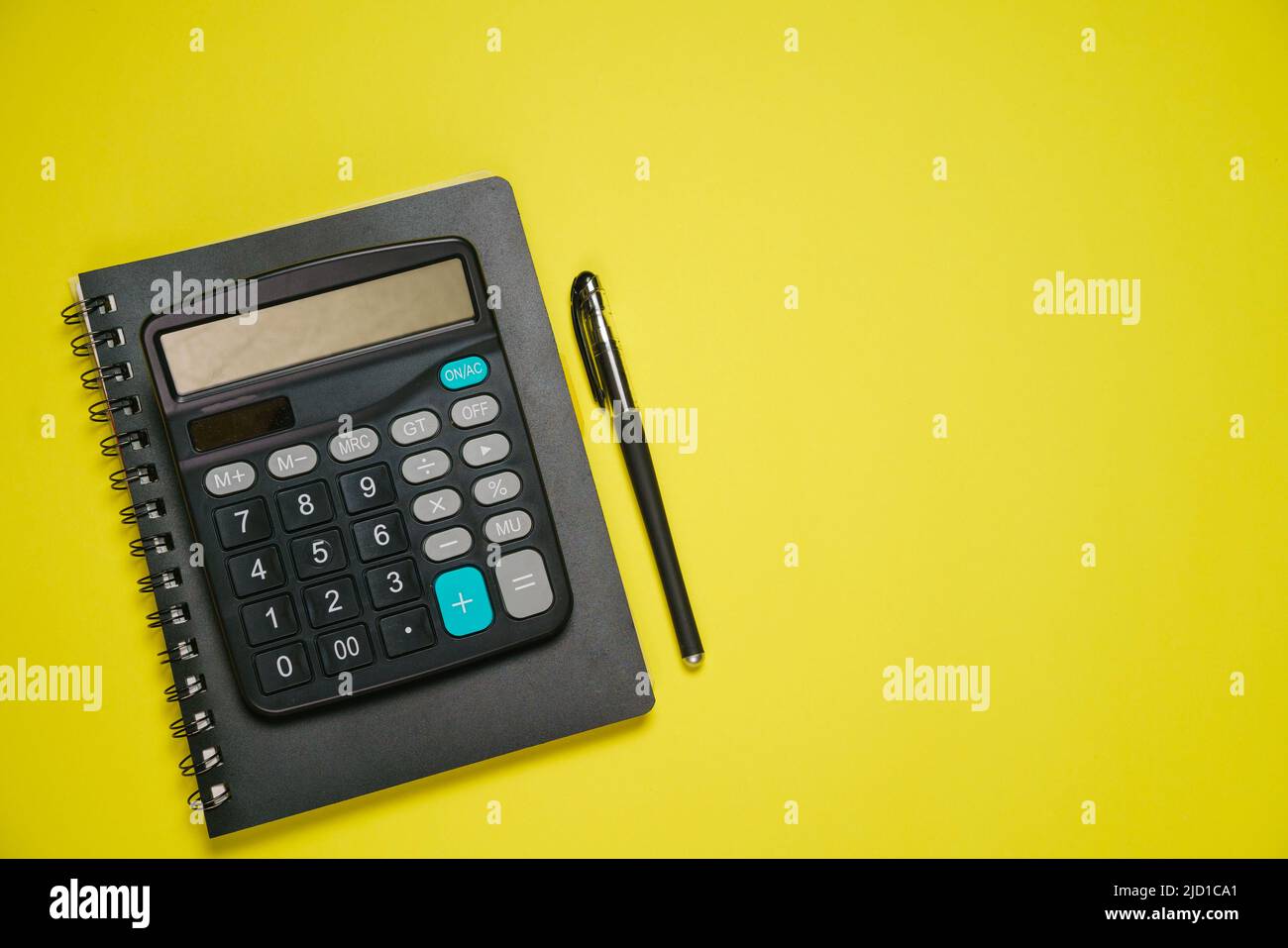 Notepad on spring black calculator and ballpoint pen on yellow ...