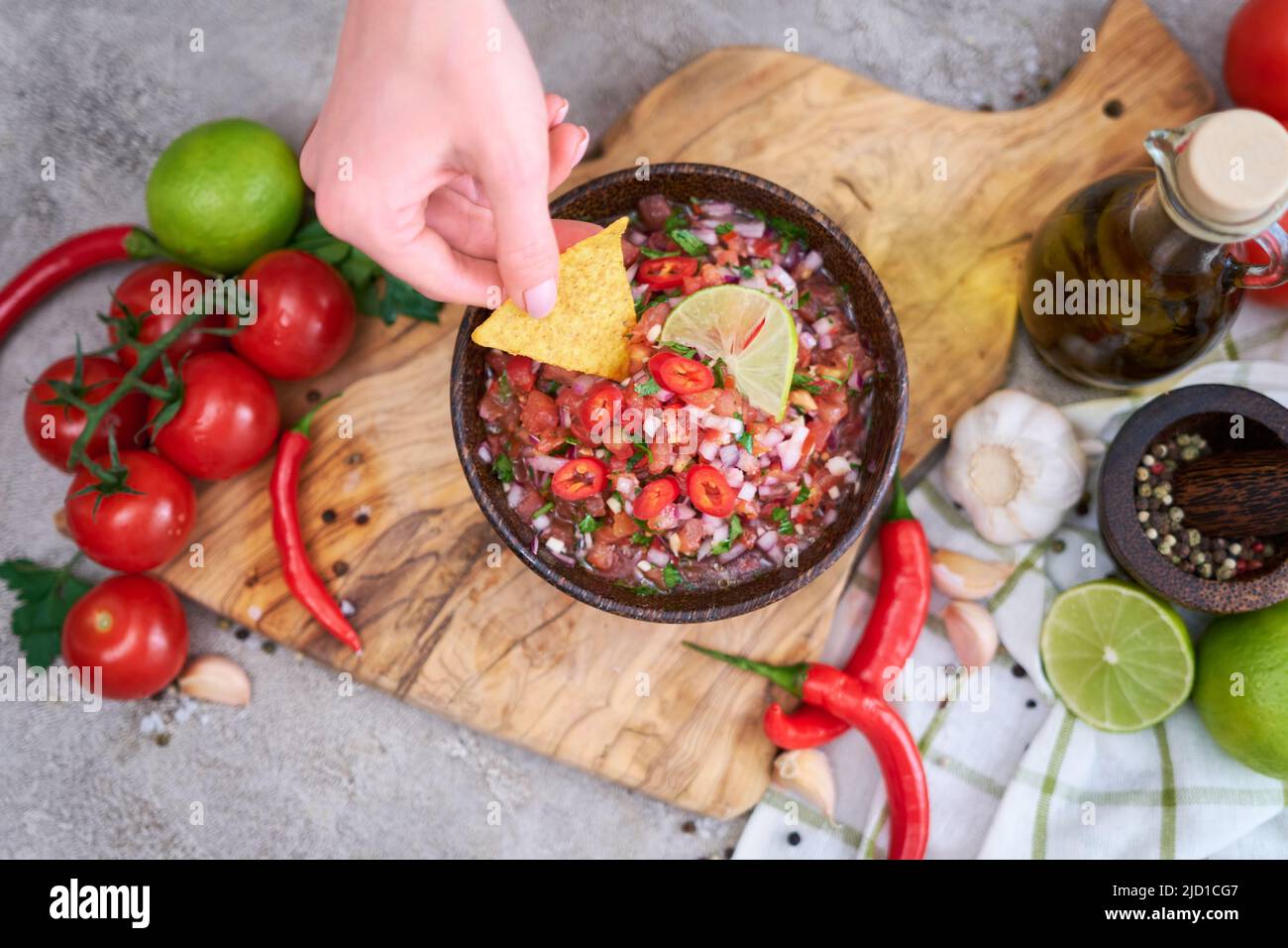 woman dips nacho chip into freshly made salsa dip sauce Stock Photo - Alamy