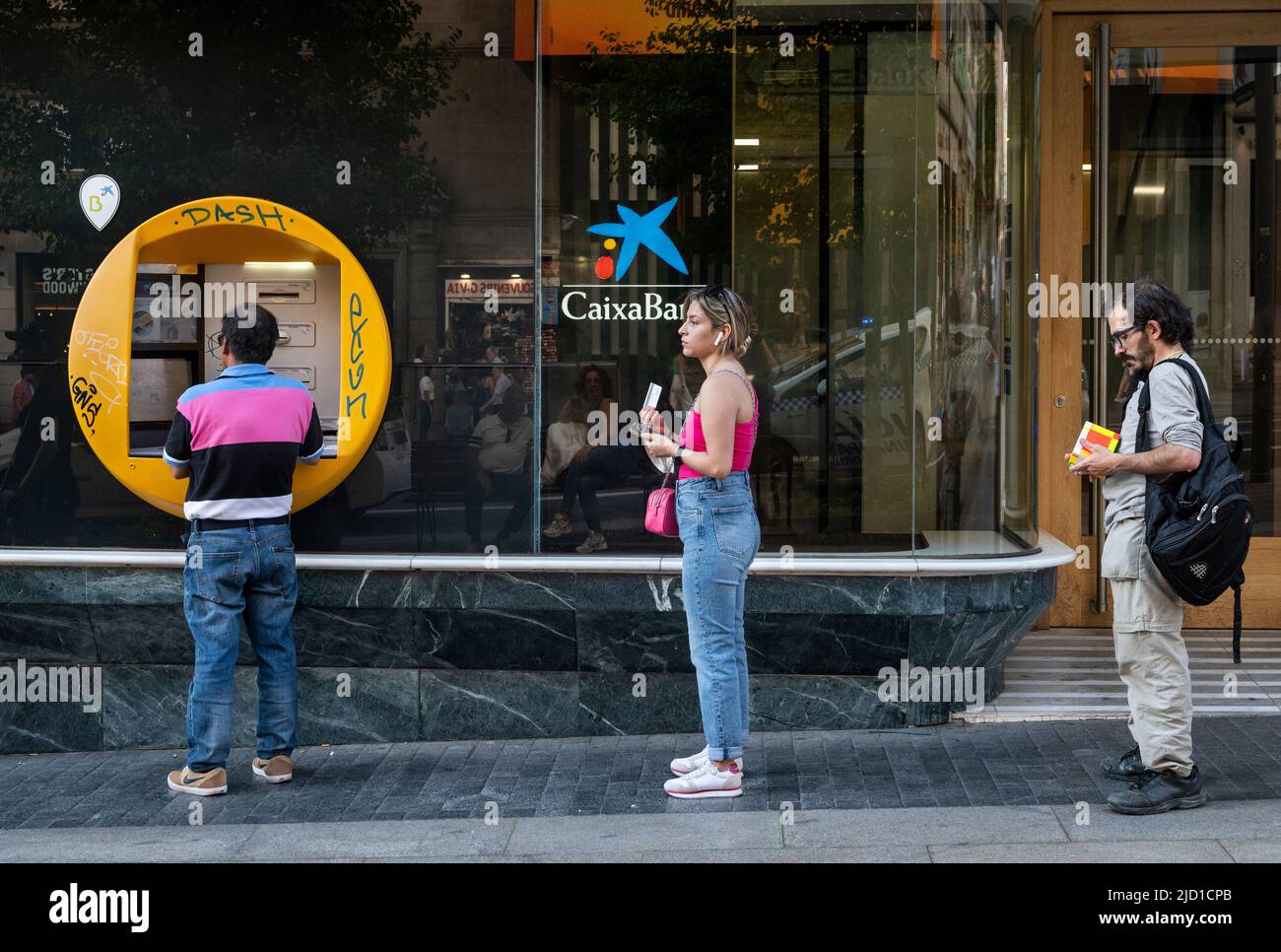 Customers are queueing in line to withdraw money from an ATM machine at the Spanish largest ...