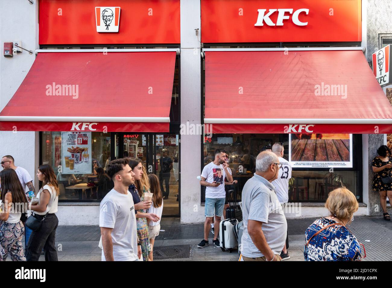 Pedestrians walk past an American fast food chicken restaurant chain ...