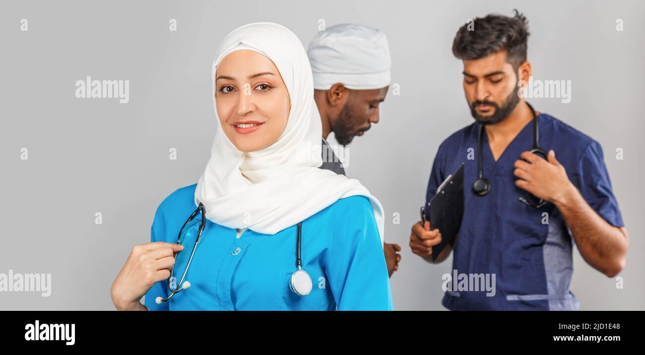 Group of paramedics smiling over gray background. muslim doctor woman ...