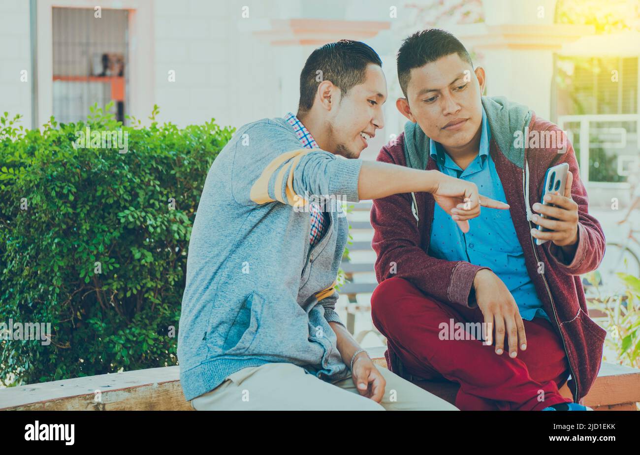 Man showing his cell phone to another guy, two guys checking their cell phones, Two young men ...