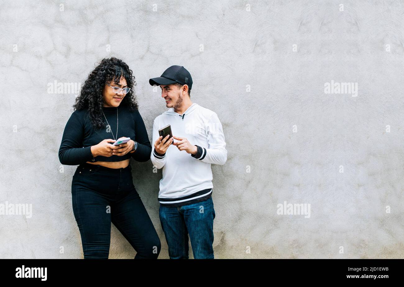 Two smiling friends checking their cell phones, Two teenage friends ...