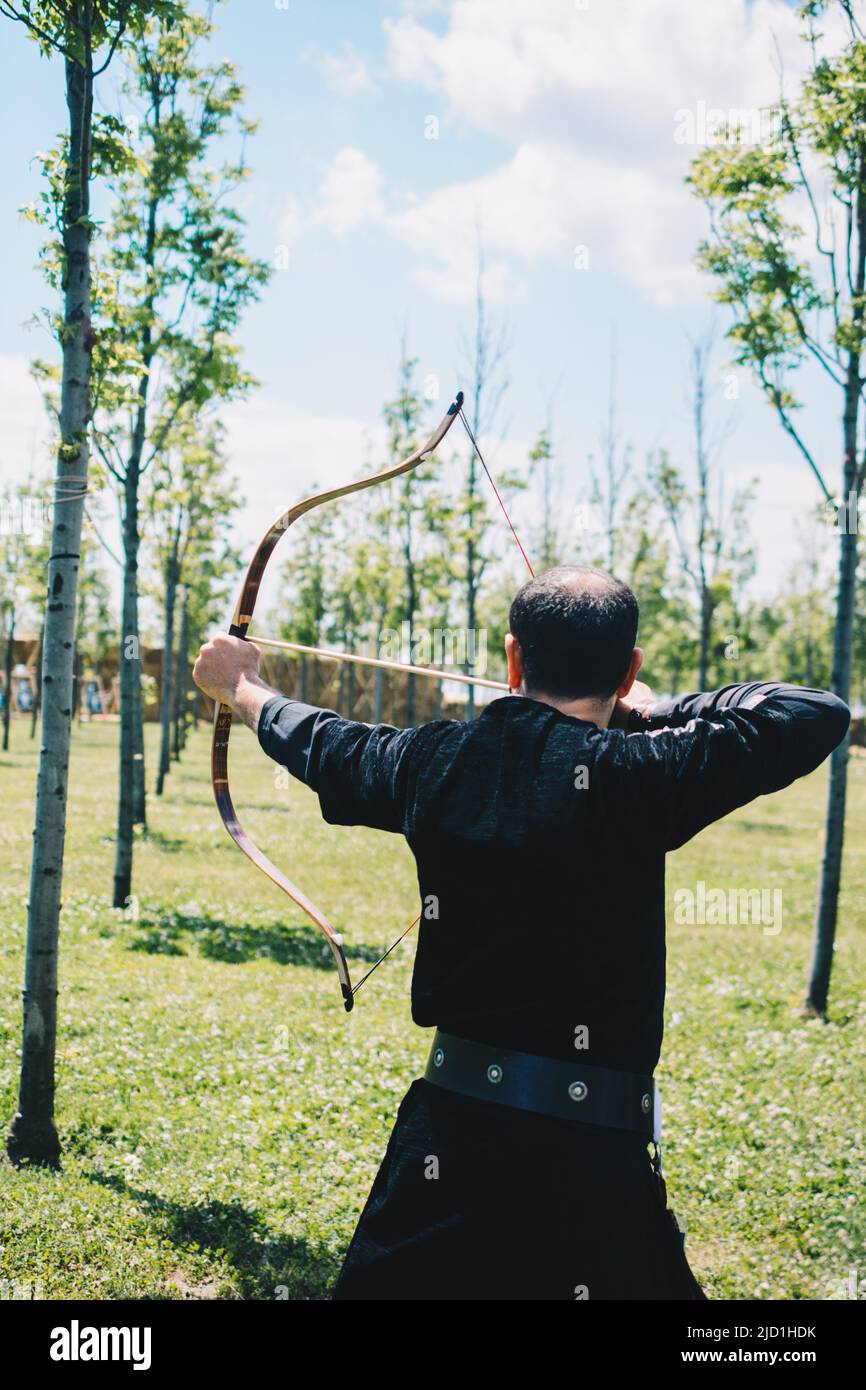 Archer with bow in traditional clothes shooting an arrow Stock Photo ...