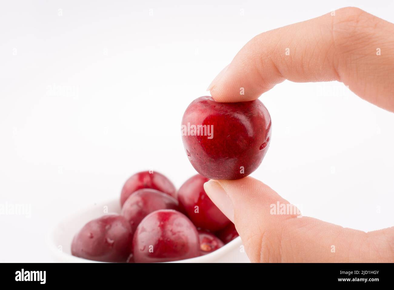 Hand holding a Cherry on a white background Stock Photo - Alamy