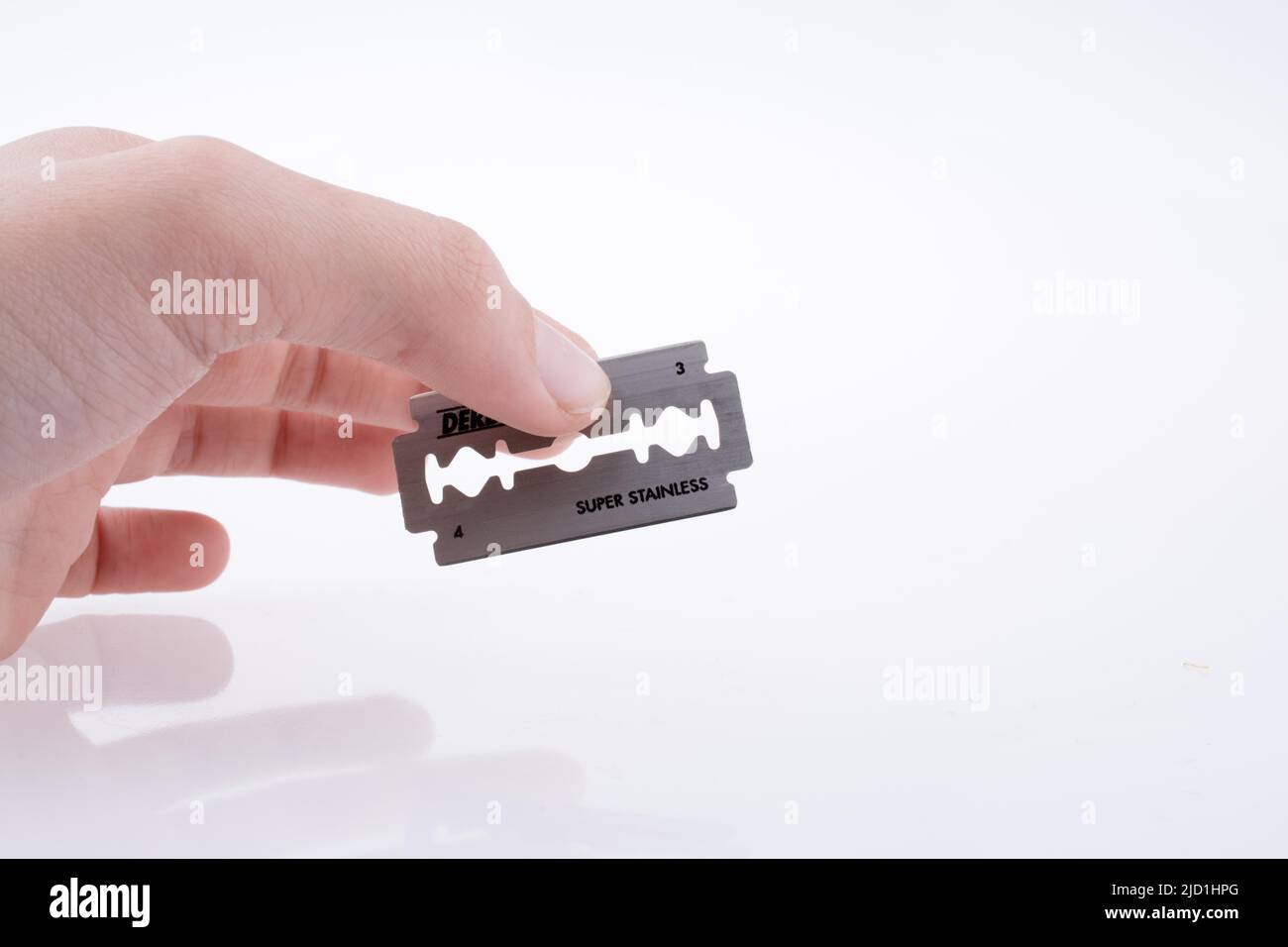 Hand holding a razor blade on a white background Stock Photo - Alamy