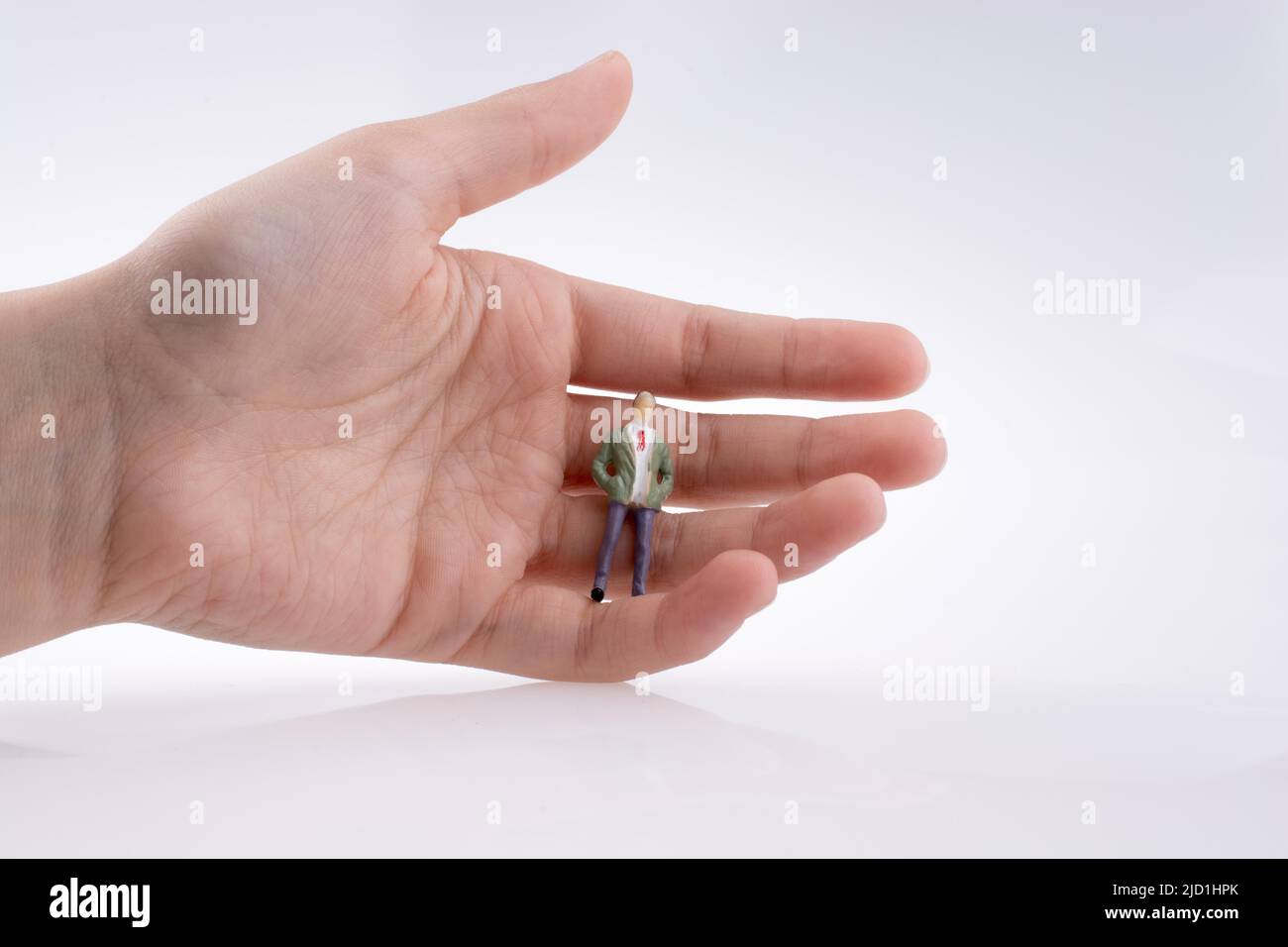 Hand holding a human figure on a white background Stock Photo - Alamy