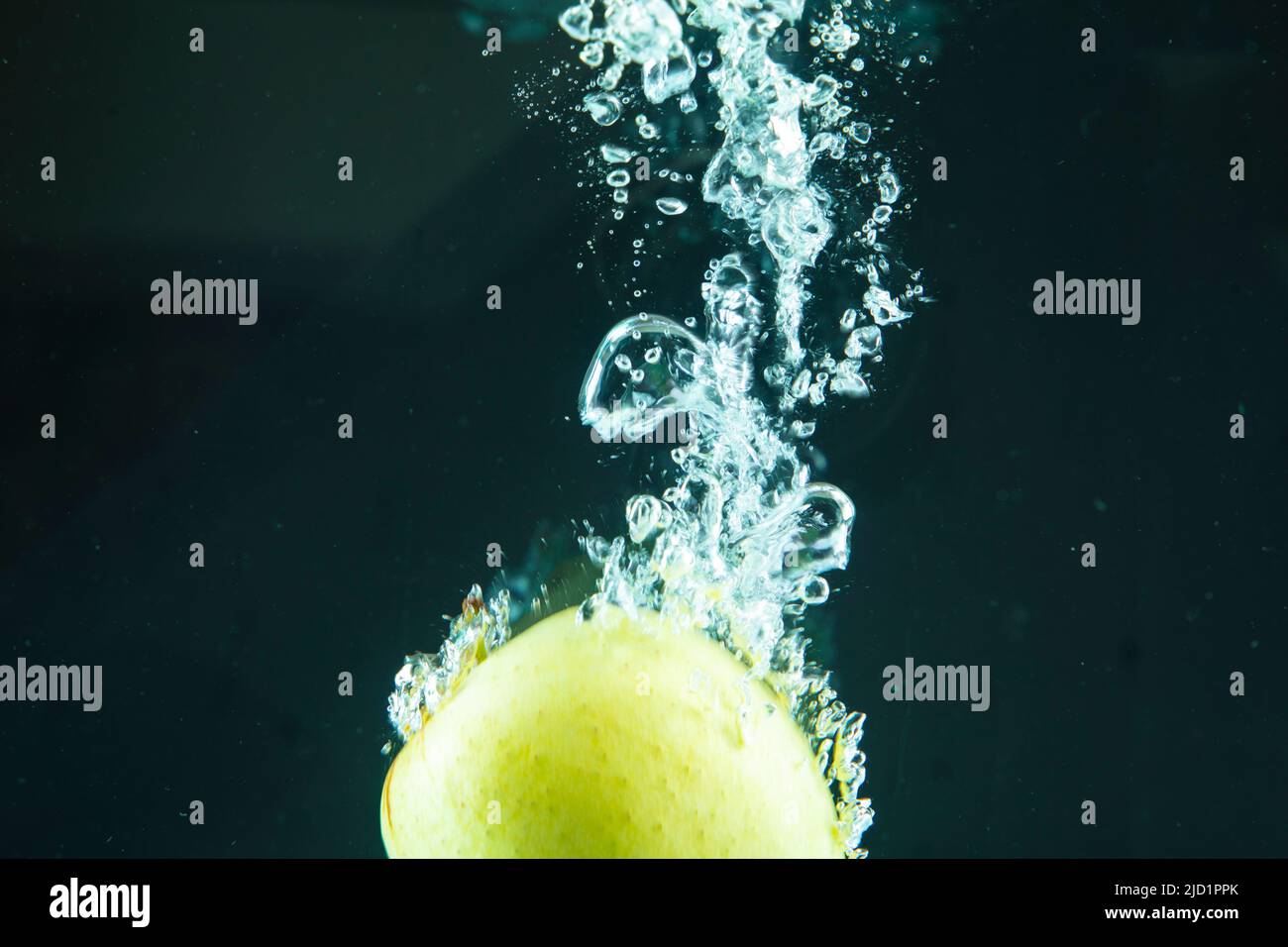 drop green apple in the tank. water is splashed on the black background ...