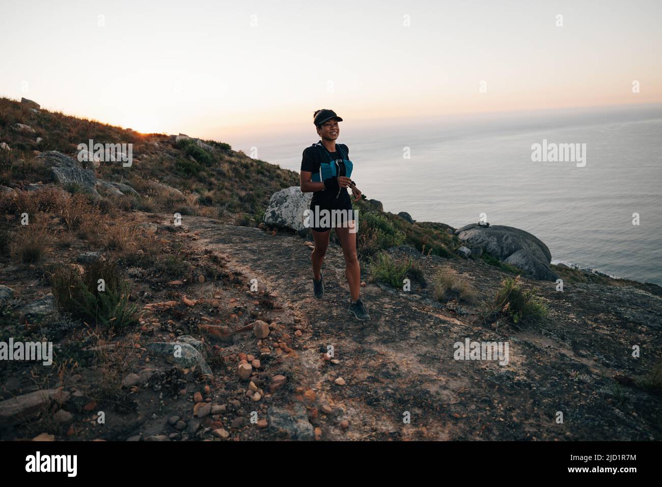 Trail runner exercising at sunset on mountain. Woman running on a hill ...