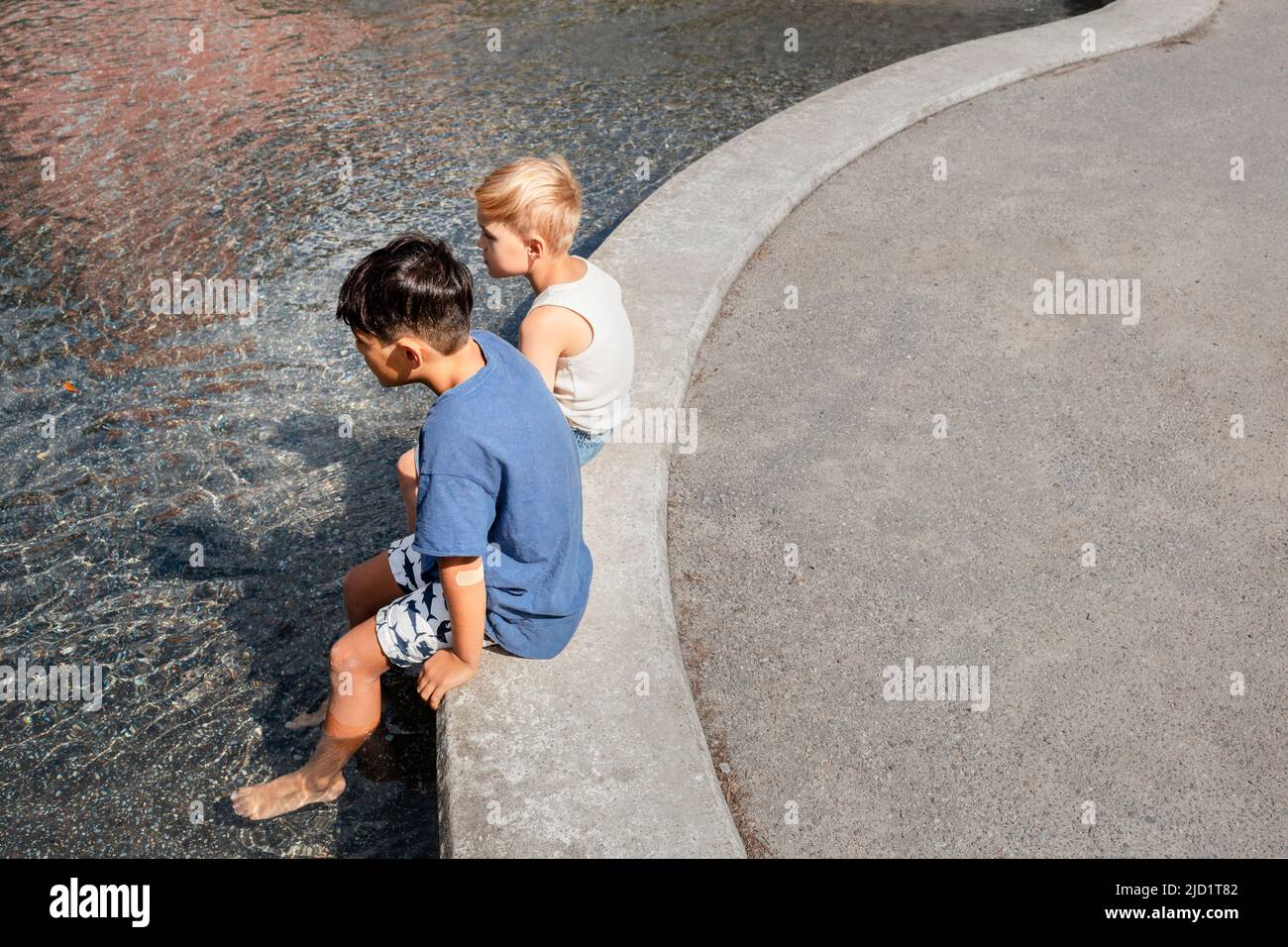 Child friends sitting with feet in pond Stock Photo - Alamy