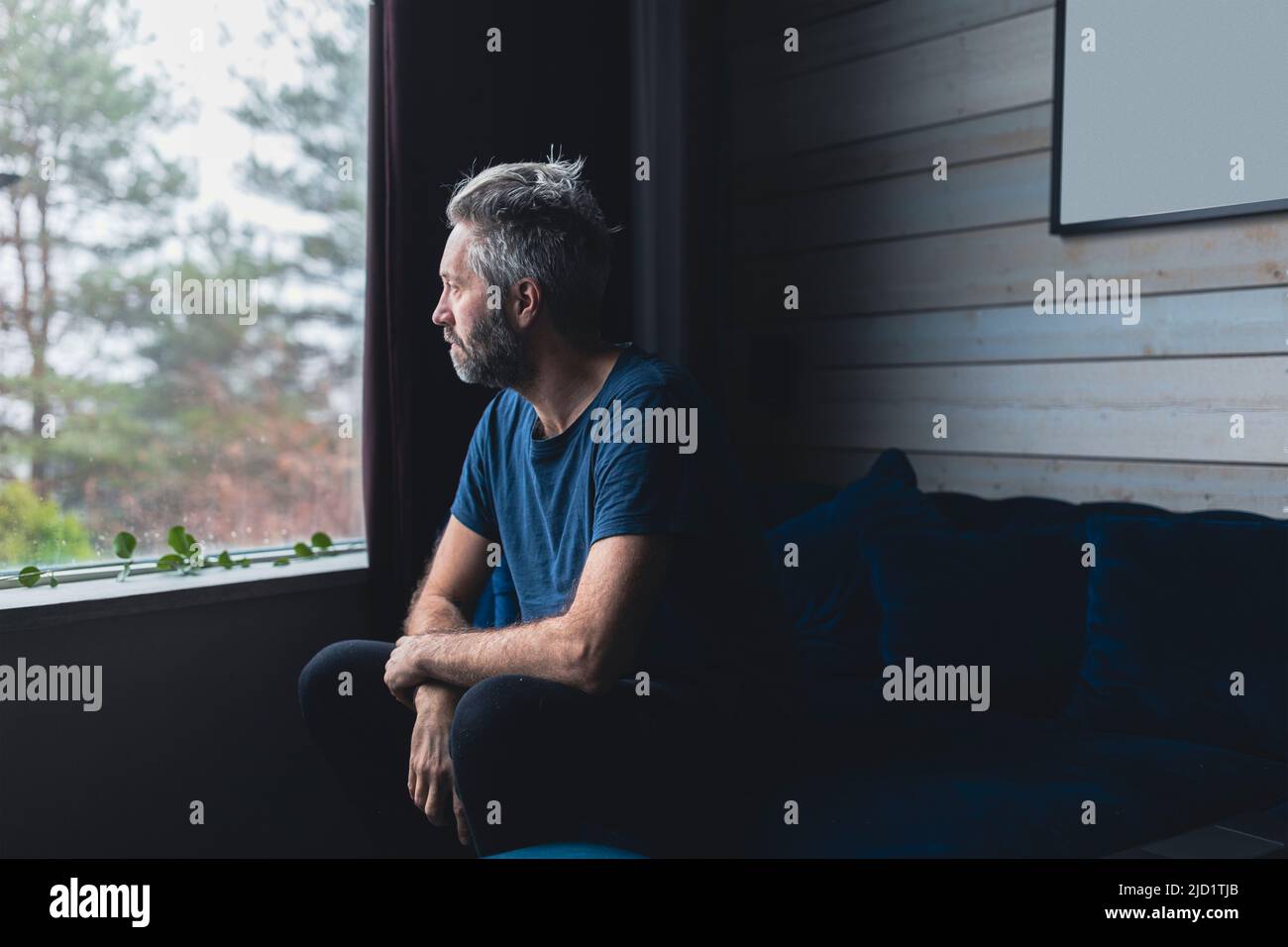 Sad man sitting on sofa Stock Photo - Alamy