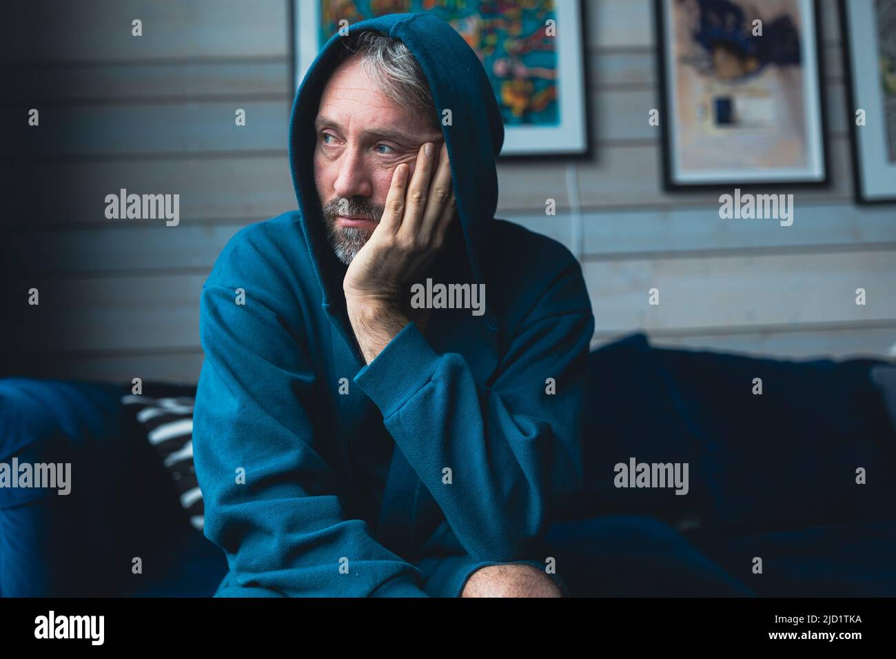 Sad man sitting on sofa Stock Photo - Alamy