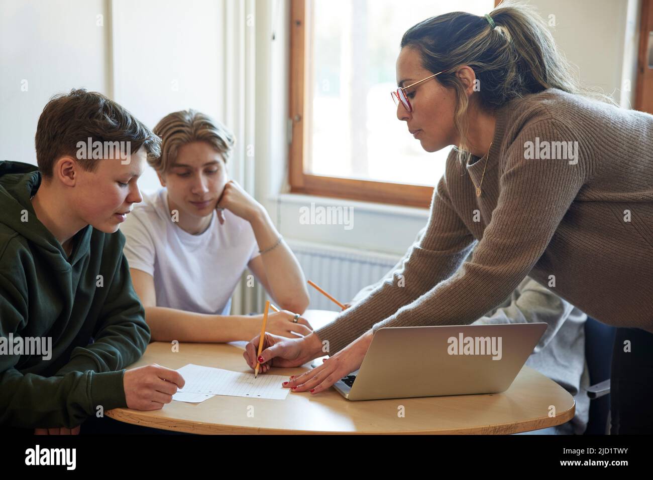 Teacher helping students in class Stock Photo - Alamy