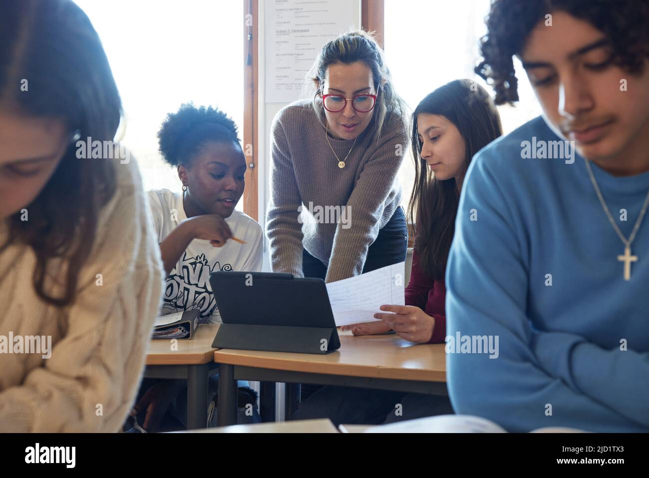 Teacher helping students in class Stock Photo - Alamy