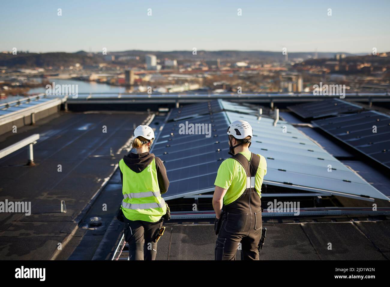 Workers standing on roof Stock Photo - Alamy