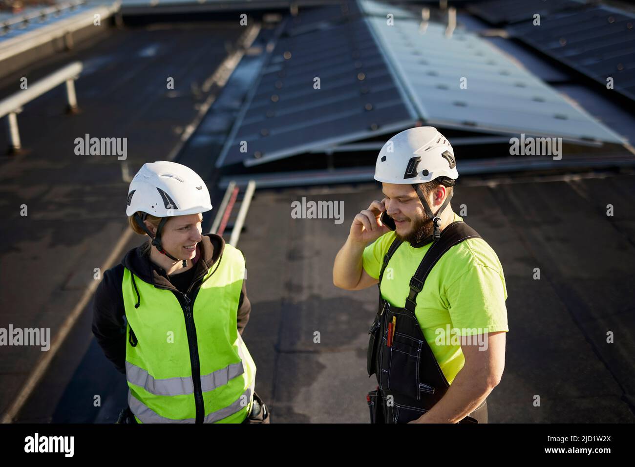 Workers standing on roof Stock Photo - Alamy
