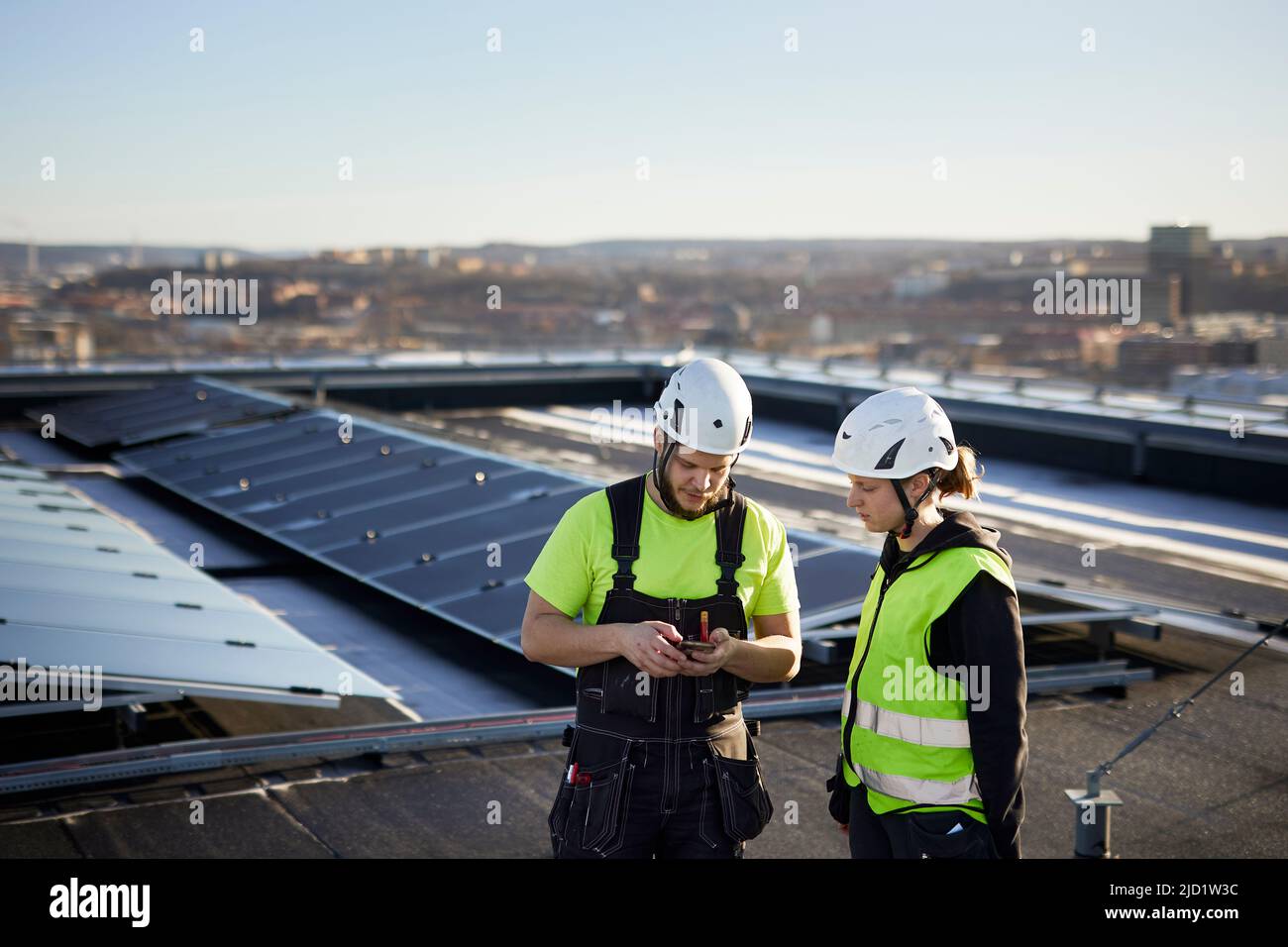 Workers standing on roof Stock Photo - Alamy