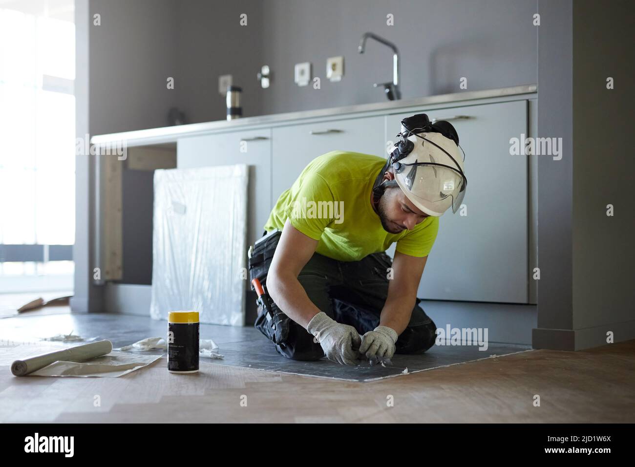 Worker installing floor in kitchen Stock Photo - Alamy