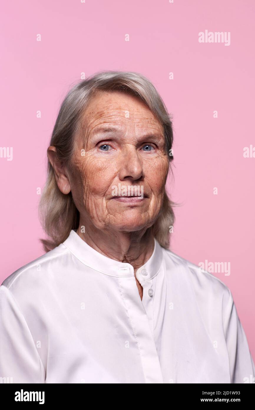 Portrait of senior woman against pink background Stock Photo - Alamy