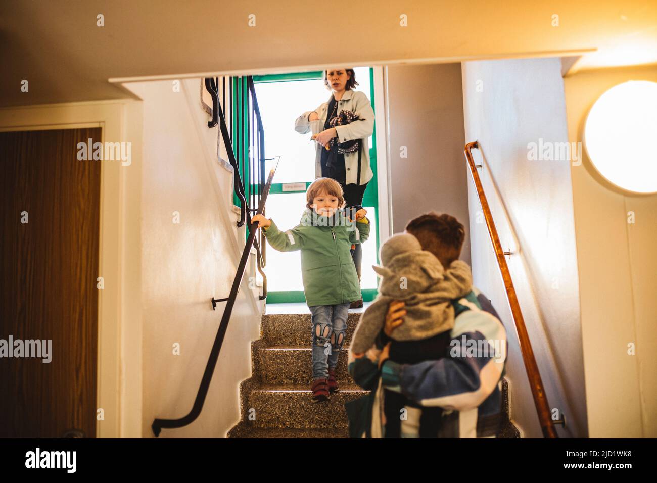Parents with children walking down staircase Stock Photo - Alamy