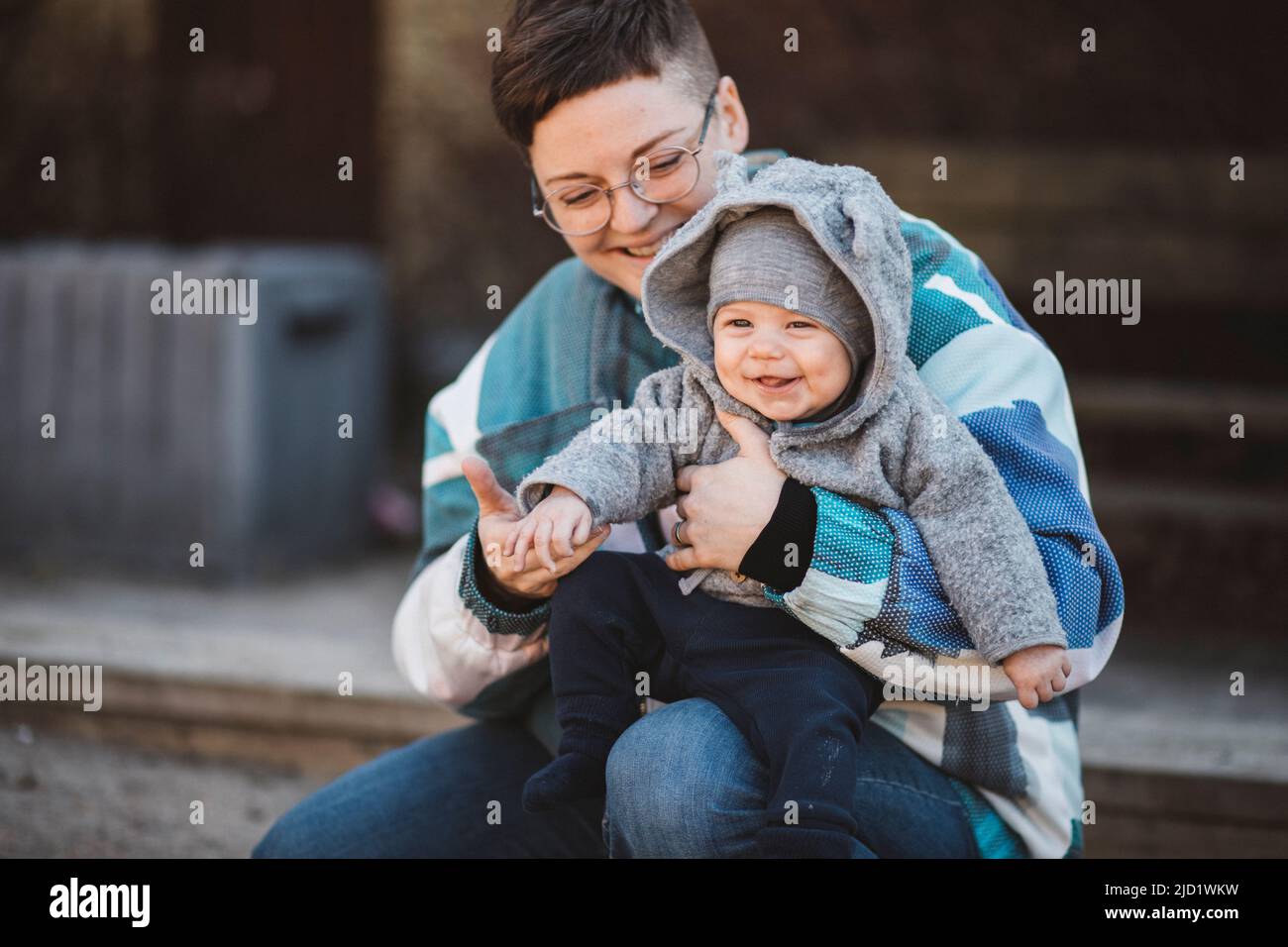 Smiling mother sitting with baby Stock Photo - Alamy