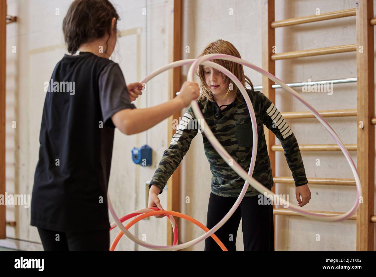 Children playing with hula hoops in school gym Stock Photo - Alamy