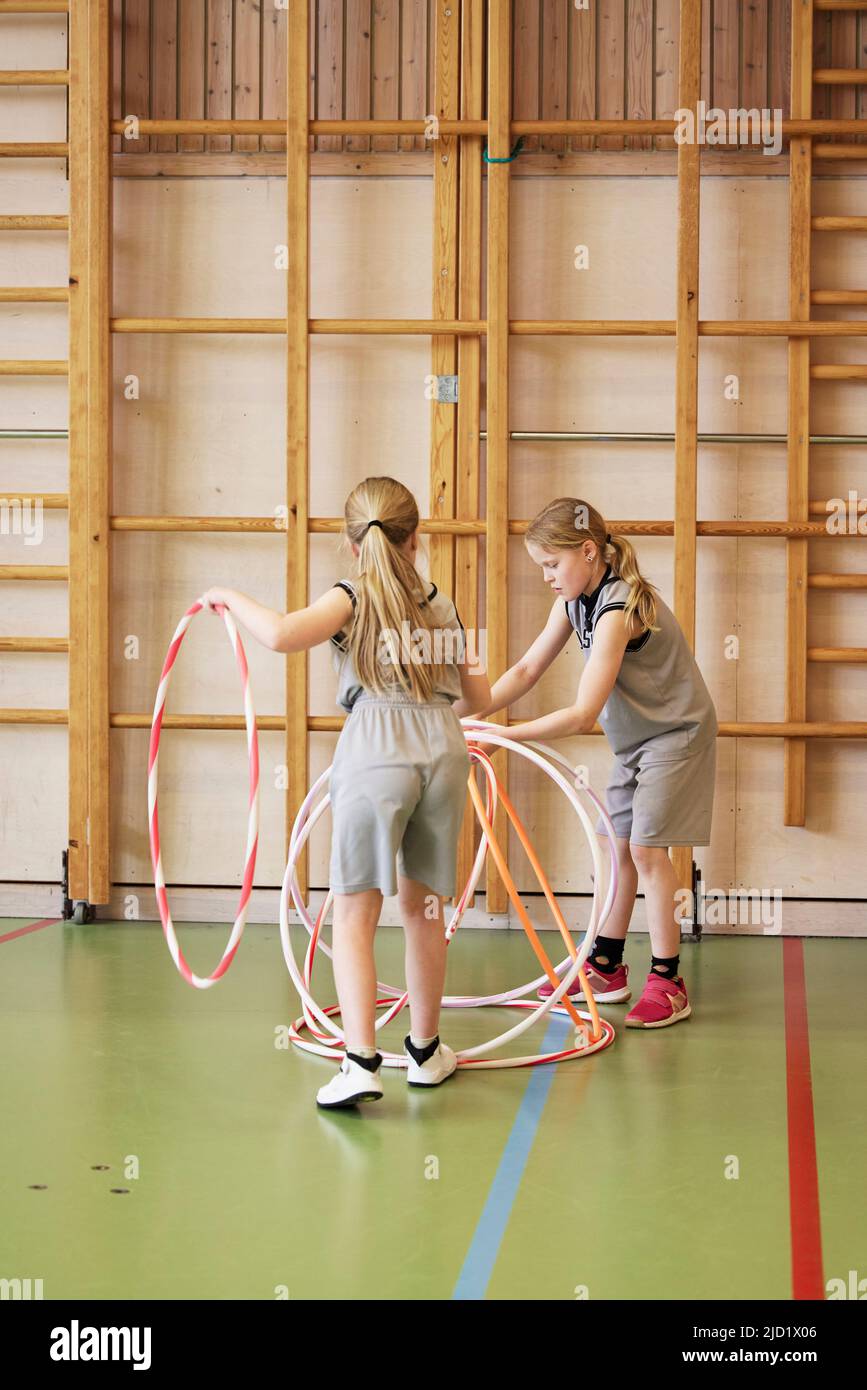 Children playing with hula hoops in school gym Stock Photo - Alamy