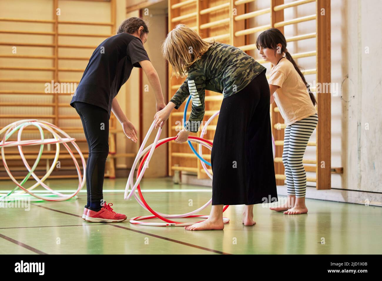 Children playing with hula hoops in school gym Stock Photo - Alamy
