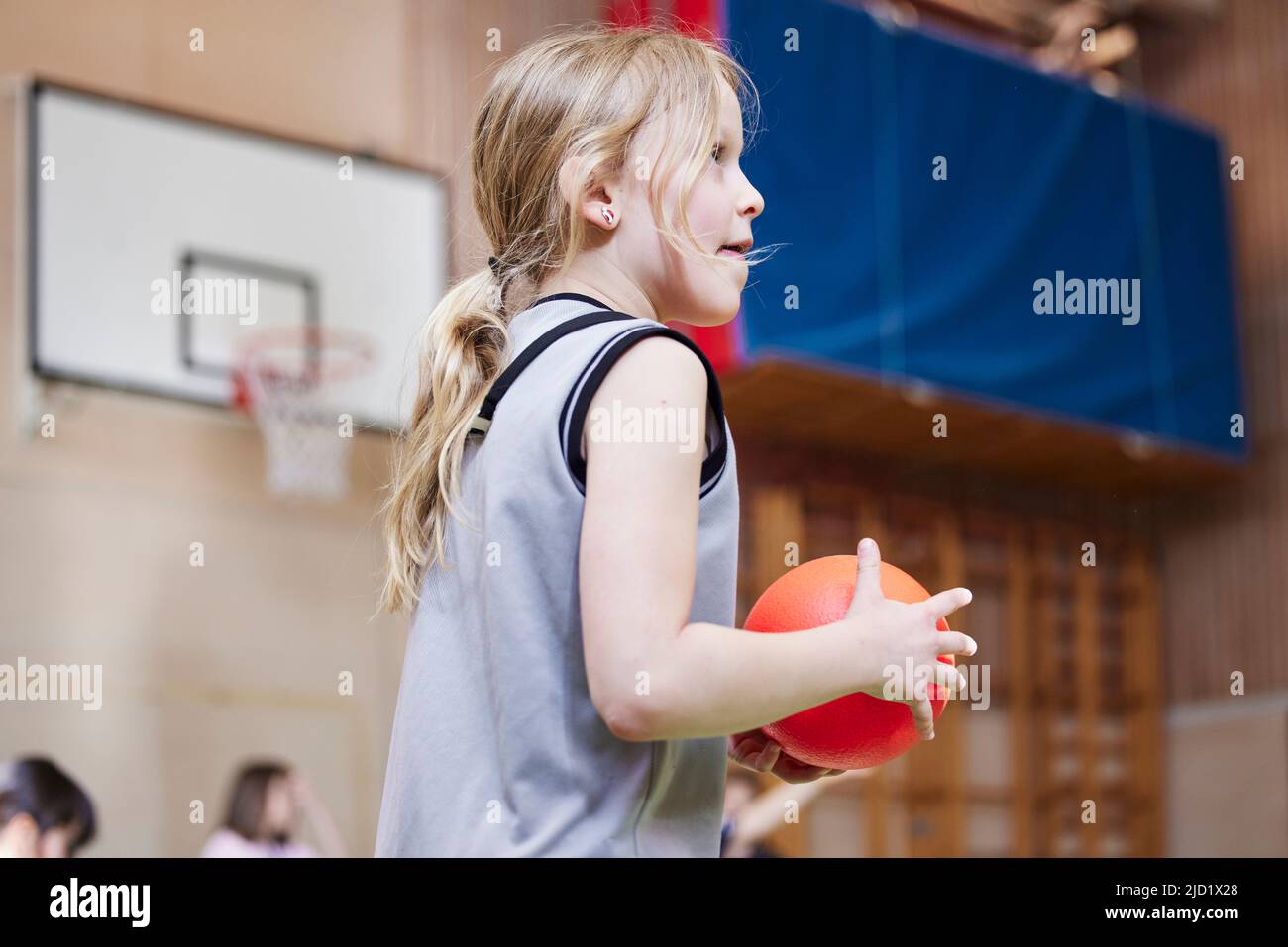 Girl holding ball during PE class in school gym Stock Photo - Alamy