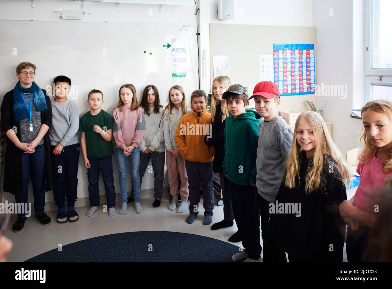 Teacher with students standing in classroom Stock Photo - Alamy