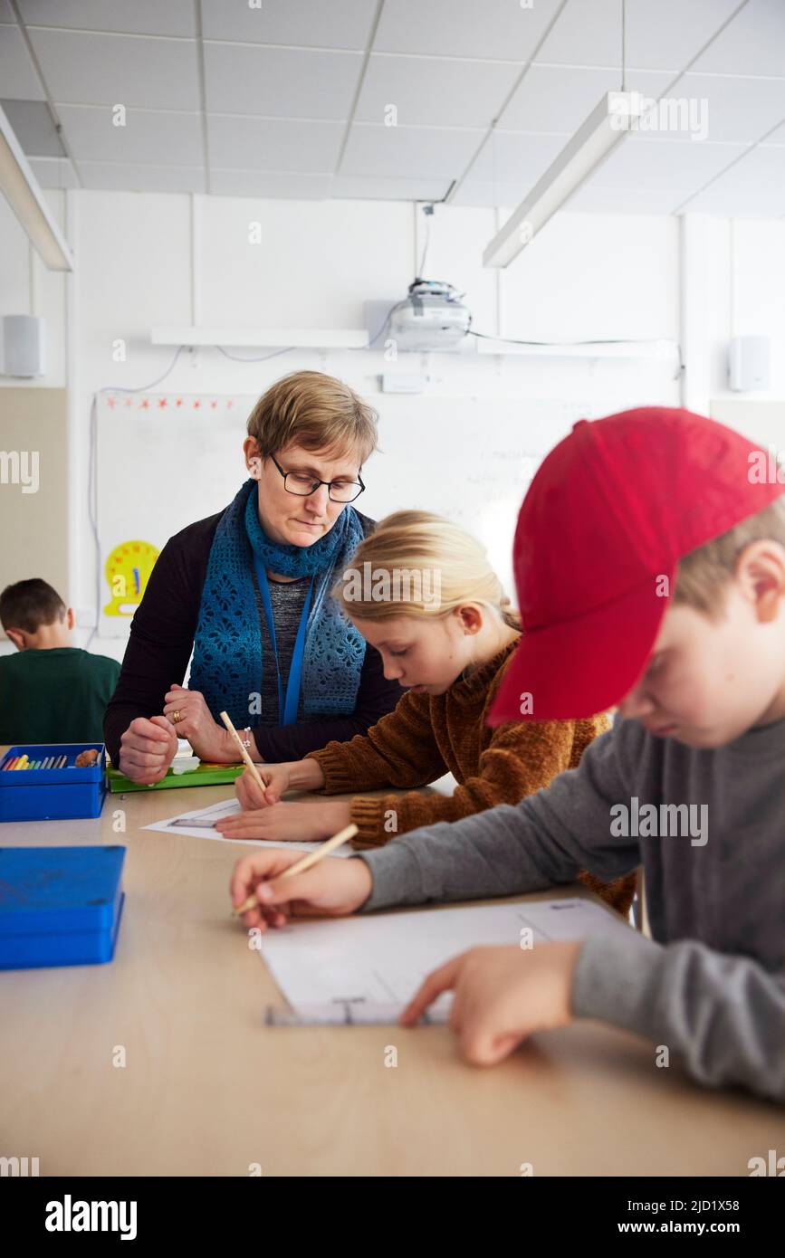 Teacher supervising students in classroom Stock Photo - Alamy
