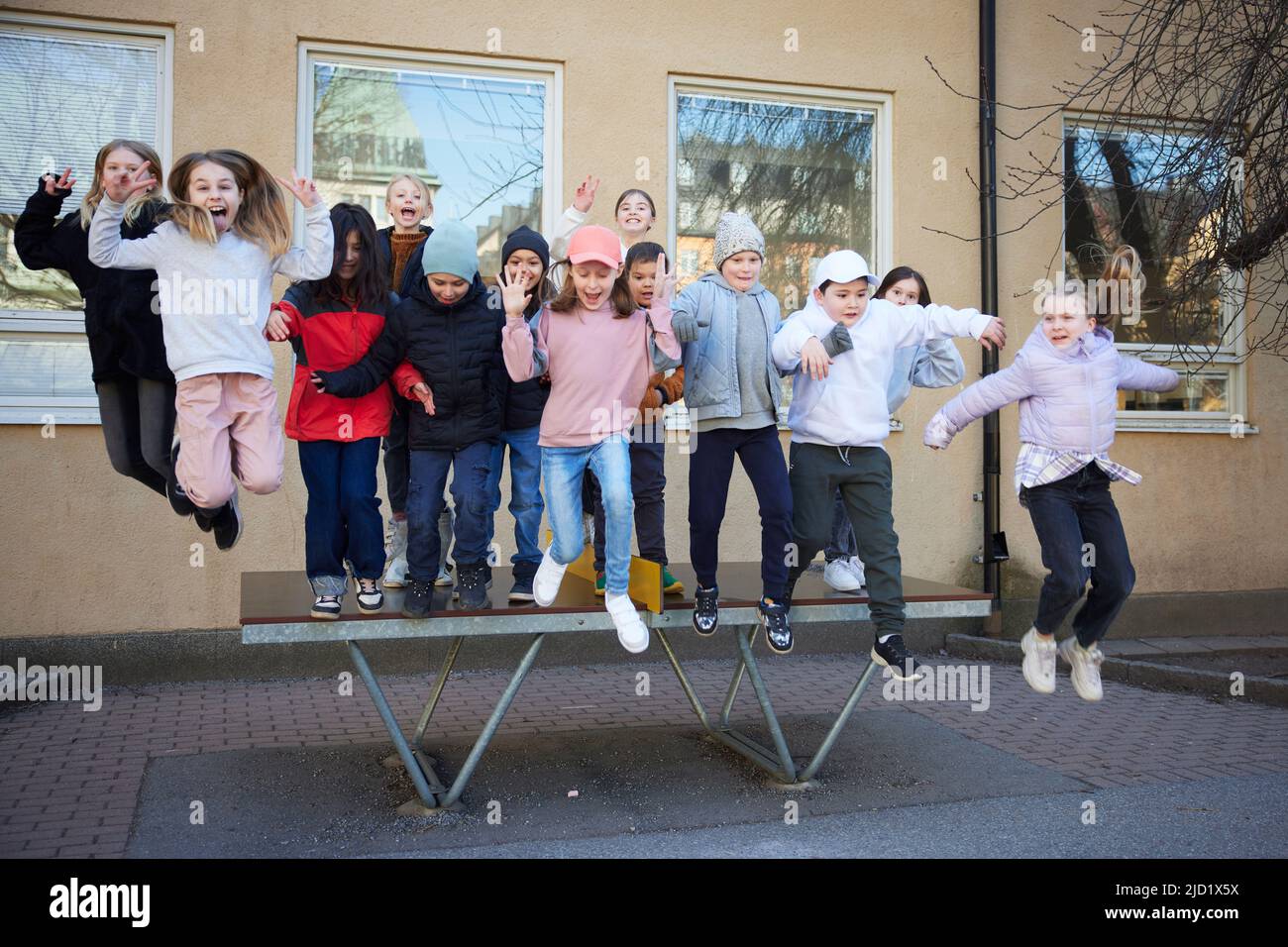 Girls and boys jumping off bench Stock Photo - Alamy